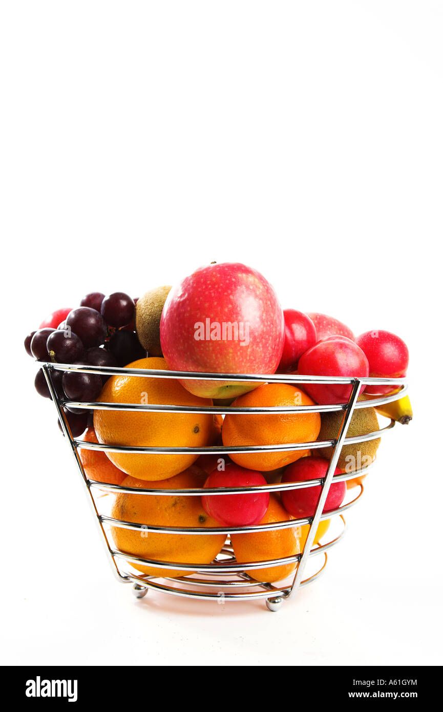 A chrome metal fruit basket full of colourful fruit including apple ...