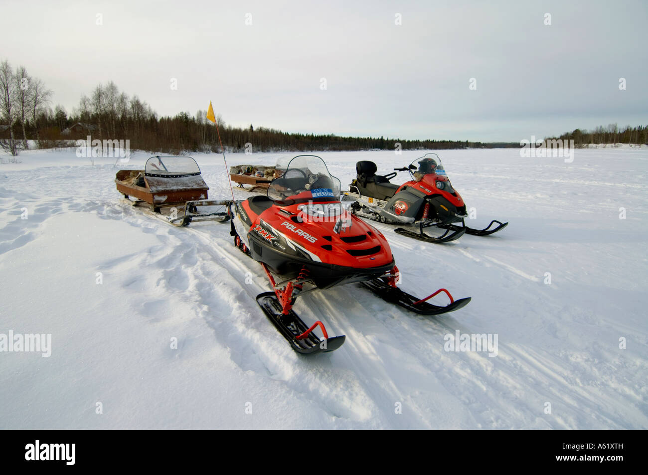 Snowmobiles towing sleighs on frozen riverbed, Luosto, Lapland ...