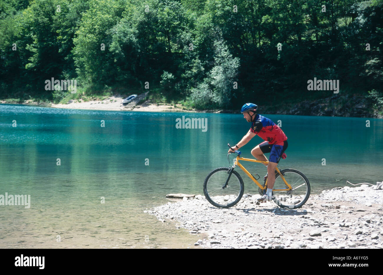 Side profile of man sitting on bicycle at lakeside, Lago di Tenno, Riva ...