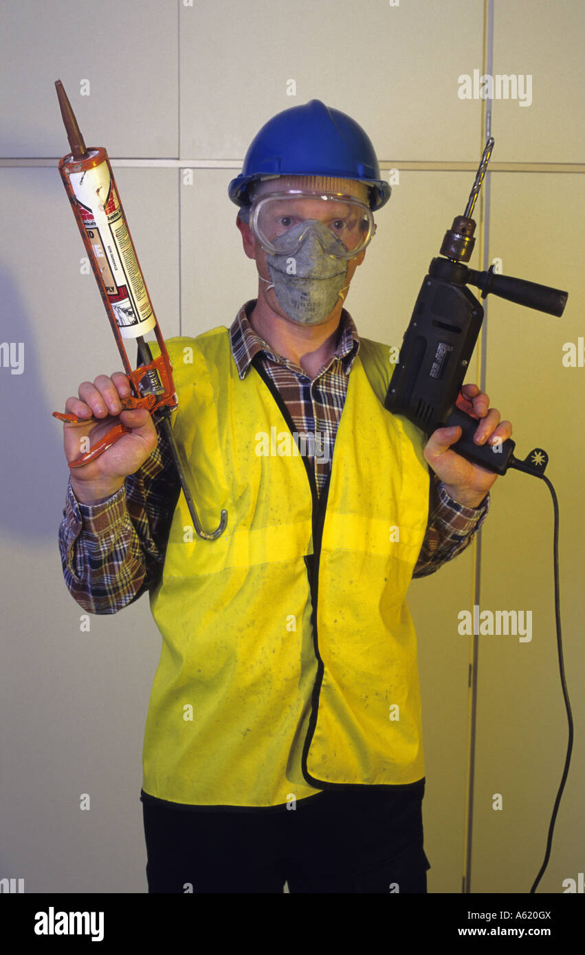 builder wearing protective safety clothing holding electric drill and ...