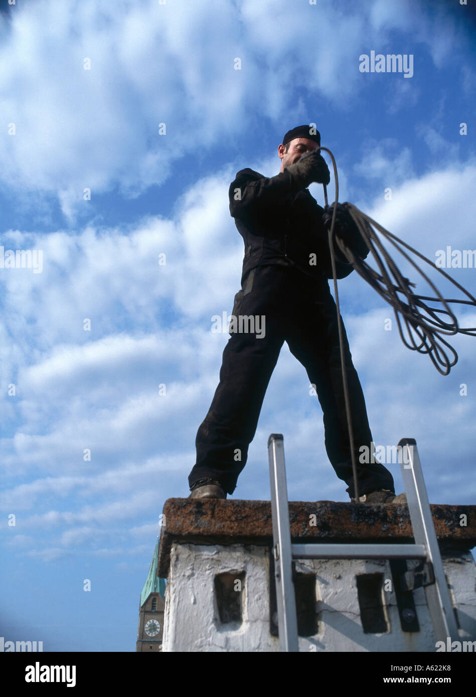 Low angle view of man cleaning chimney at top of building Stock Photo ...