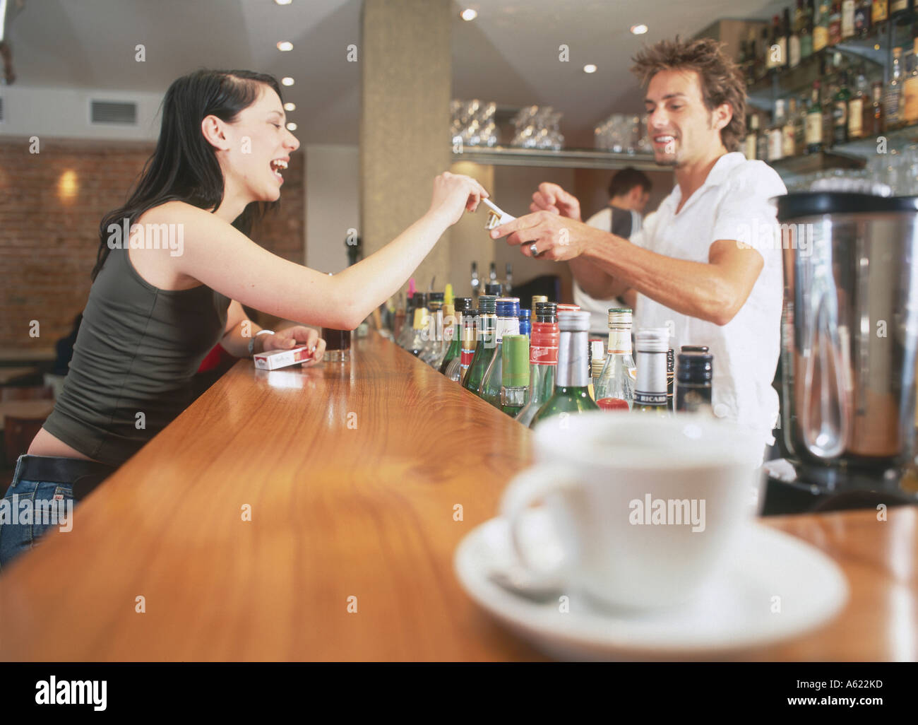 Male bartender serving woman cigarette at bar Stock Photo - Alamy