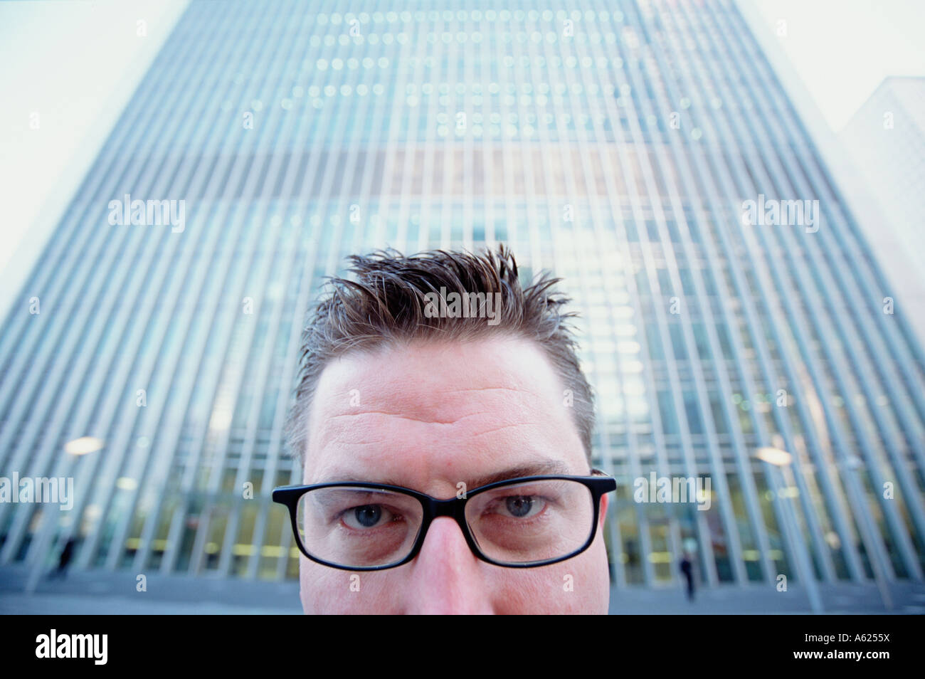 Close Up Businessman staring direct at camera with an office block ...