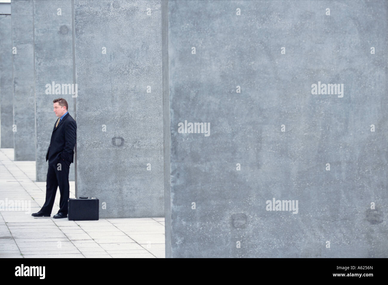 businessman with briefcase waiting in grey environment Stock Photo - Alamy