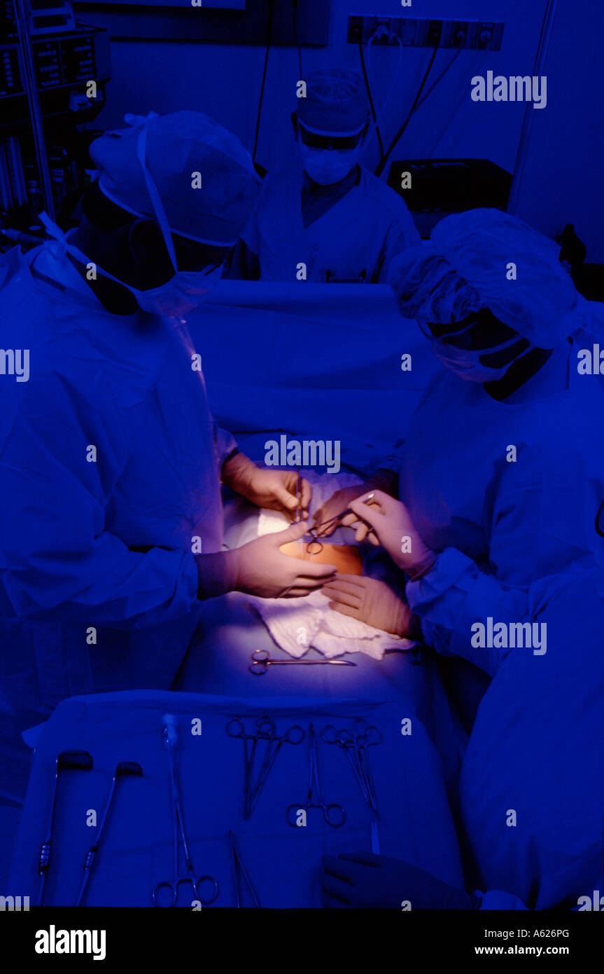 A doctor is handed a clamp from a nurse in an operating room during a ...