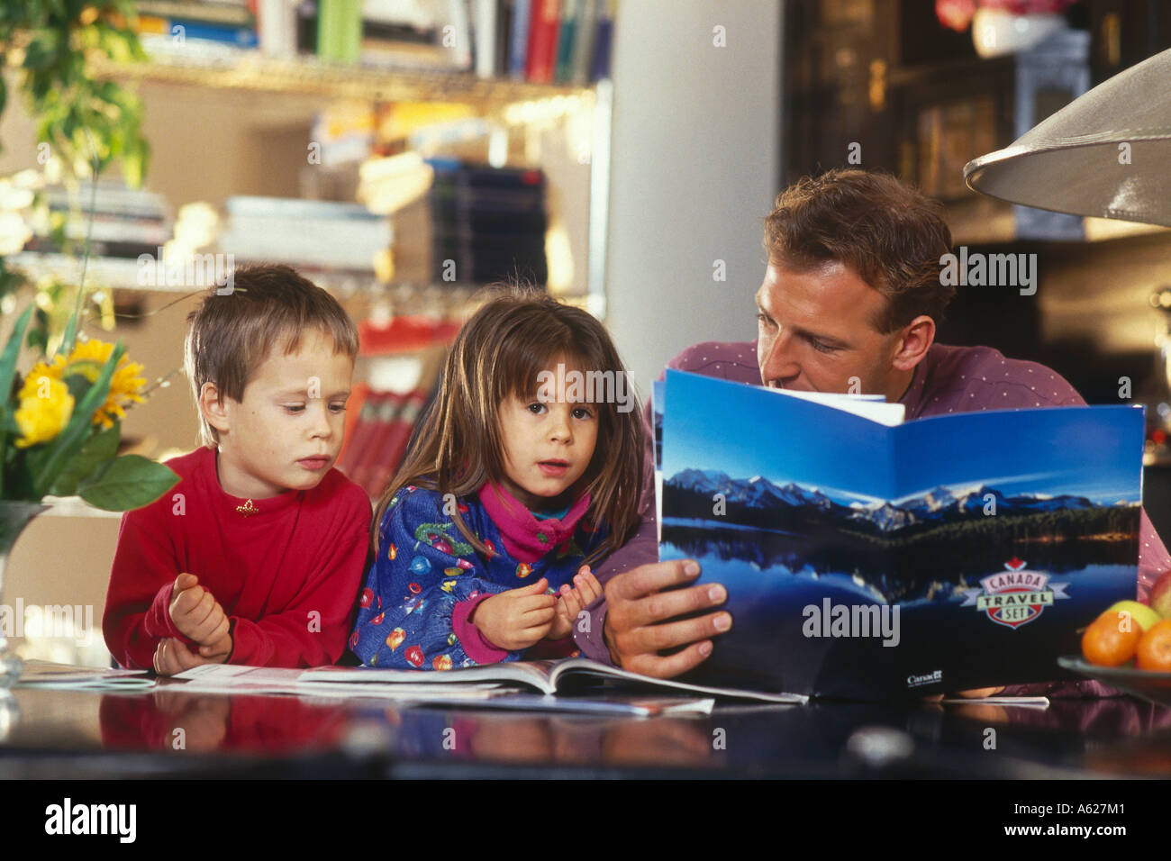 Man and his children reading books in living room Stock Photo - Alamy