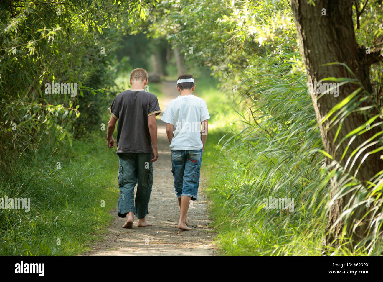 two boys walking along a forest path in their bare feet Stock Photo - Alamy