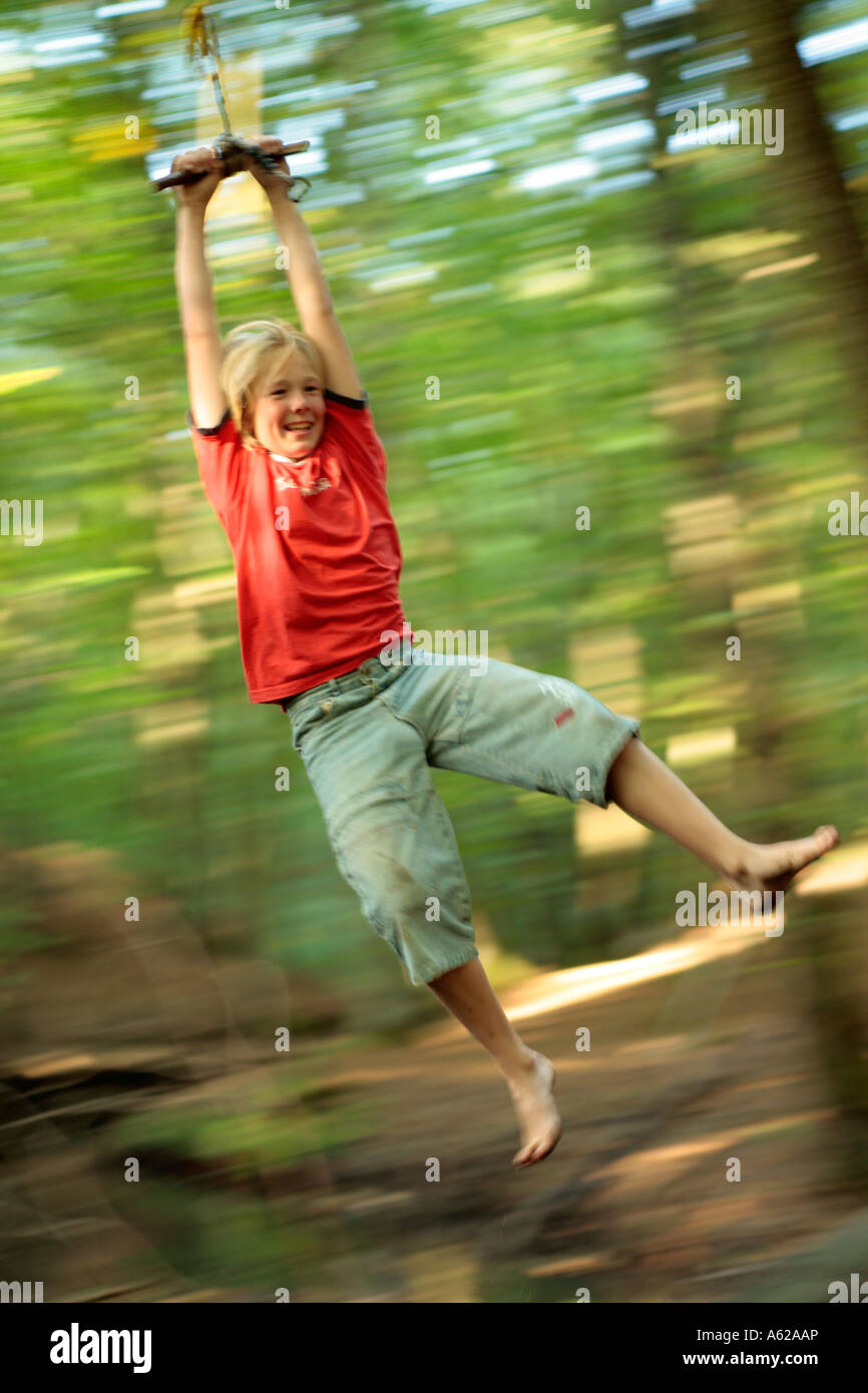 a young boy swinging on a rope in a forest Stock Photo - Alamy