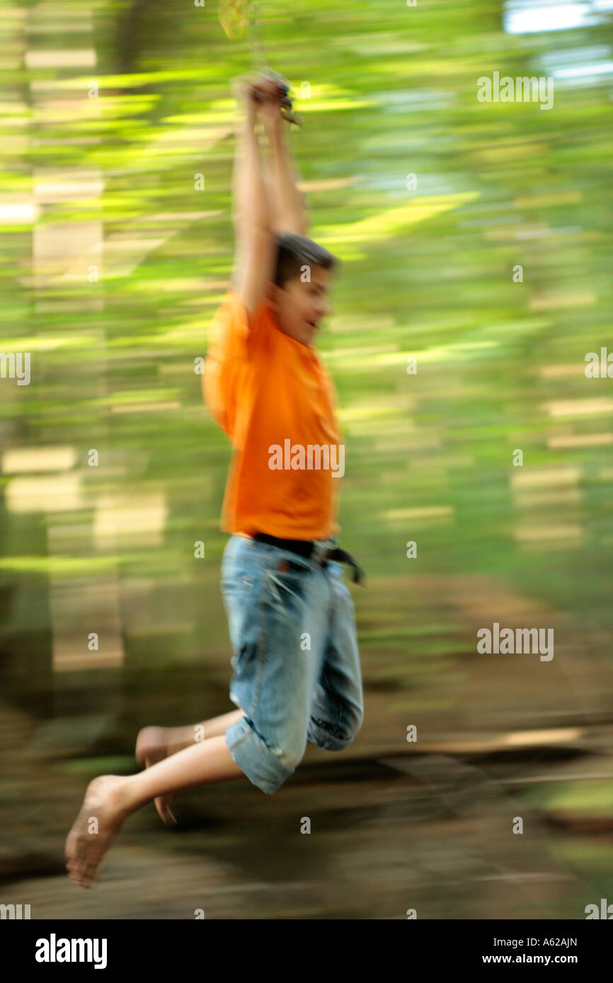 a young boy swinging on a rope in a forest Stock Photo - Alamy
