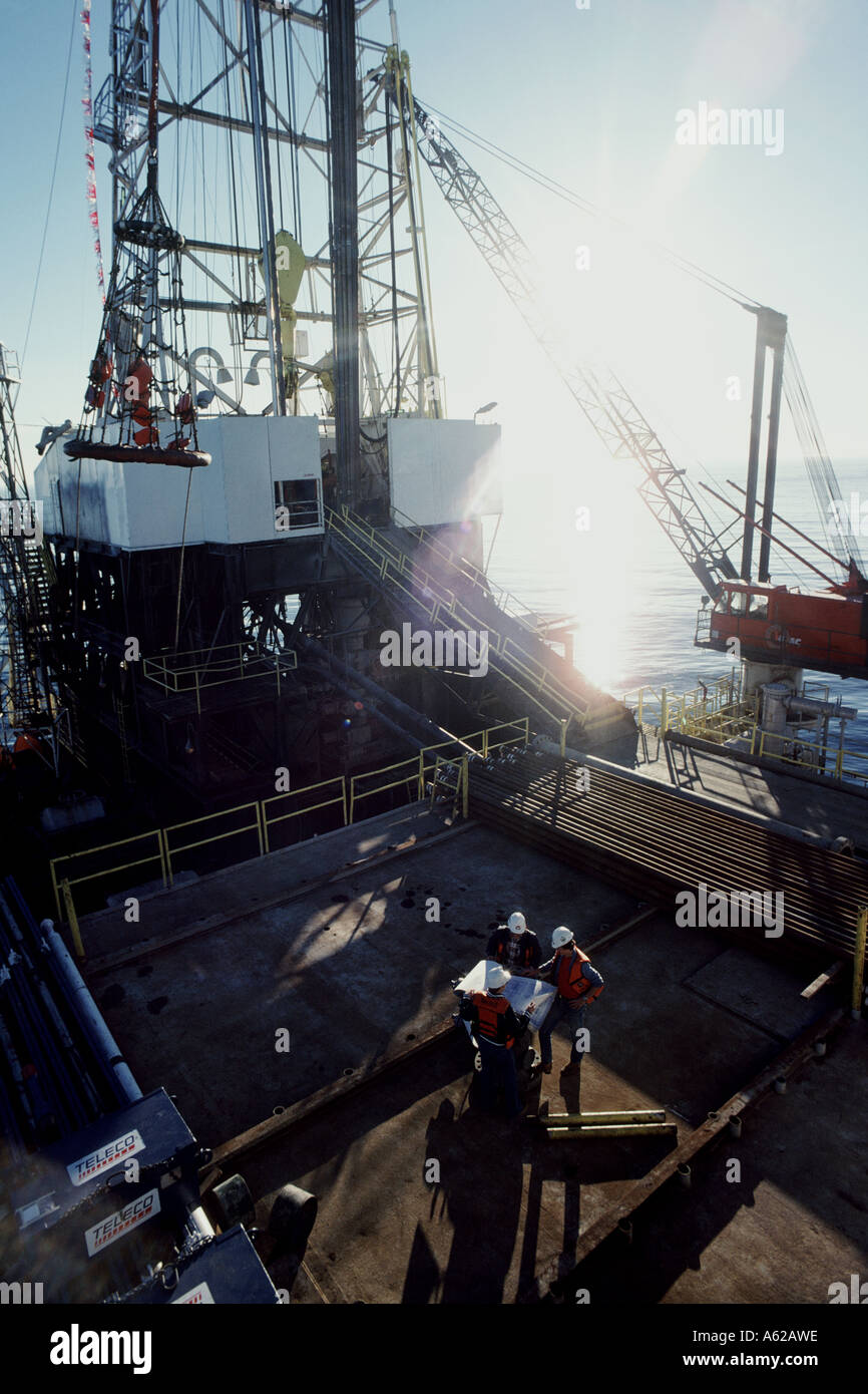 Two men look at blueprints on an off shore oil rig in the Gulf Of ...