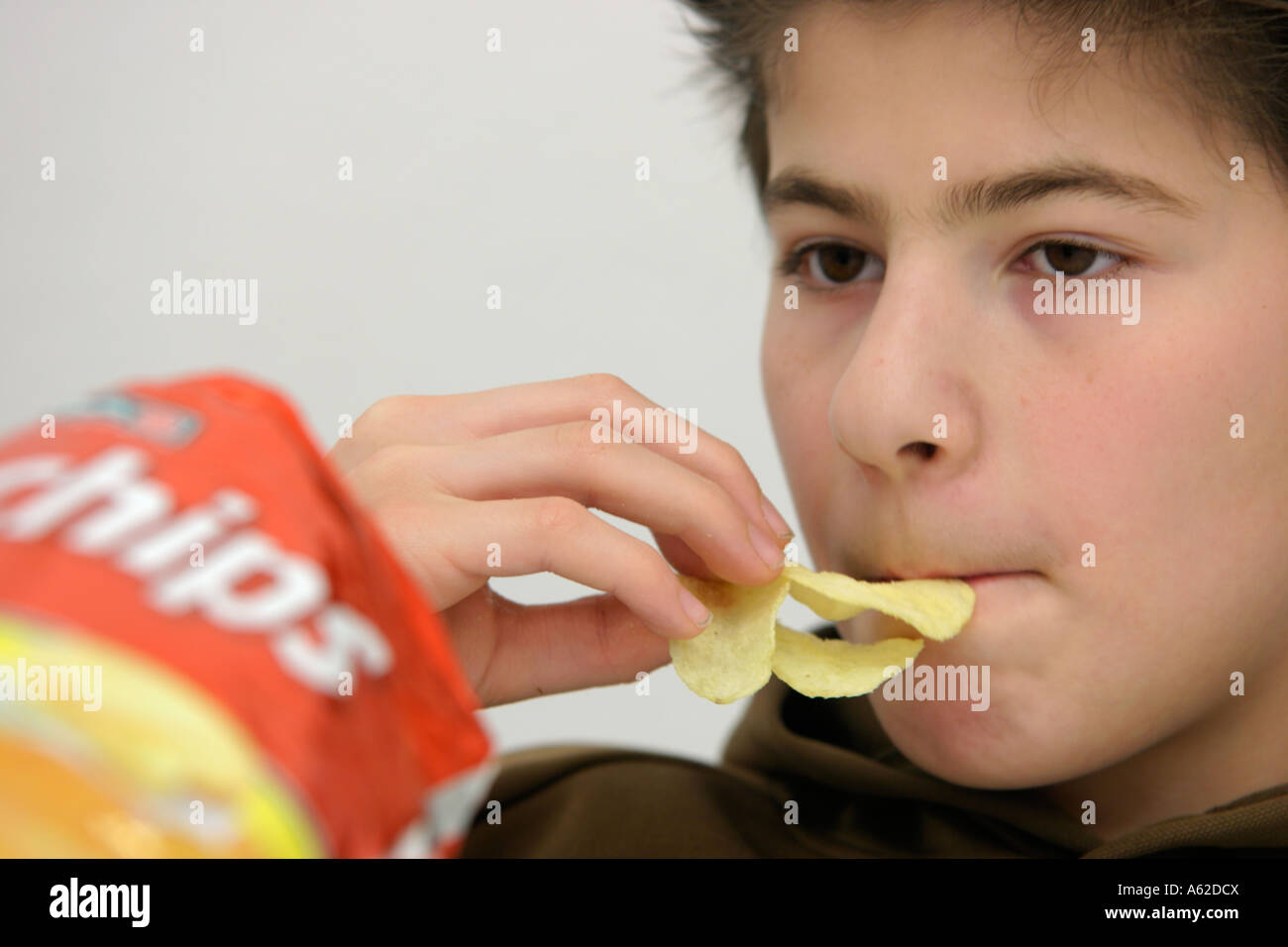 portrait of an absorbed young boy eating crisps Stock Photo - Alamy