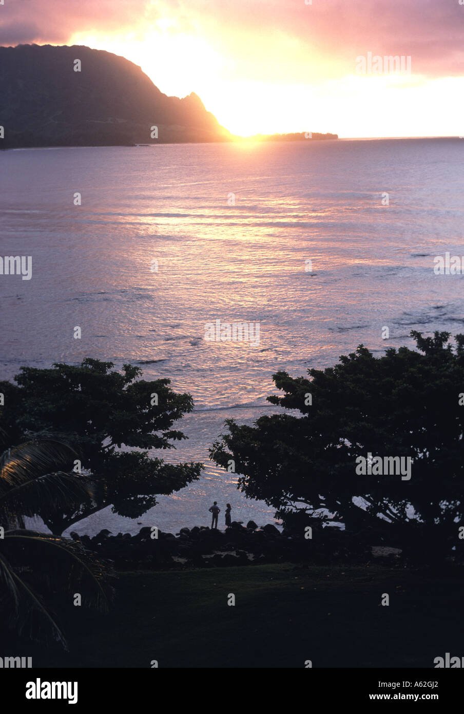 A honeymoon couple watches the sunset behind Diamond Head on the Island ...