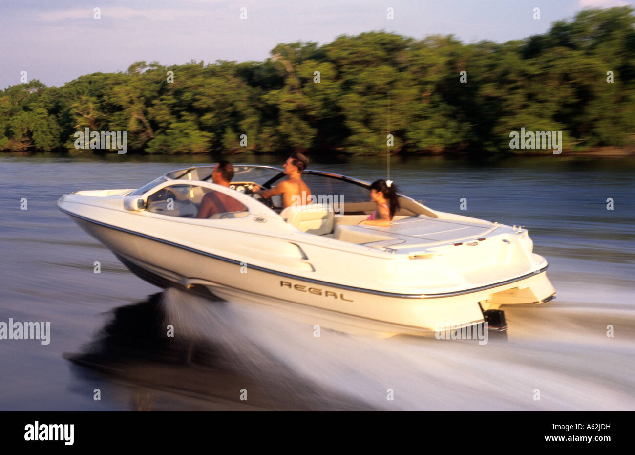 Couples running motor boat with wake and excitement as it moves thru ...