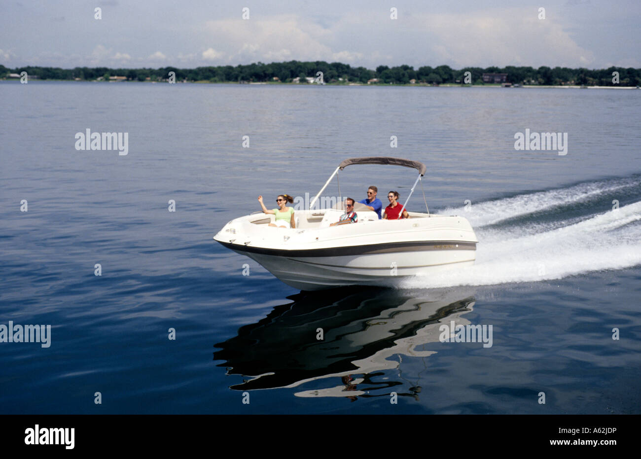 Couples running motor boat with wake and excitement as it moves thru ...