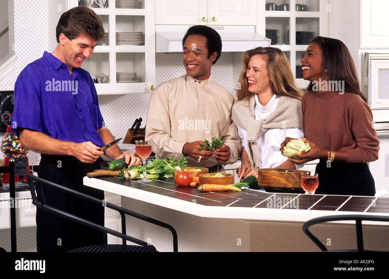 Black and white couples dating and relaxing at home cooking in kitchen ...