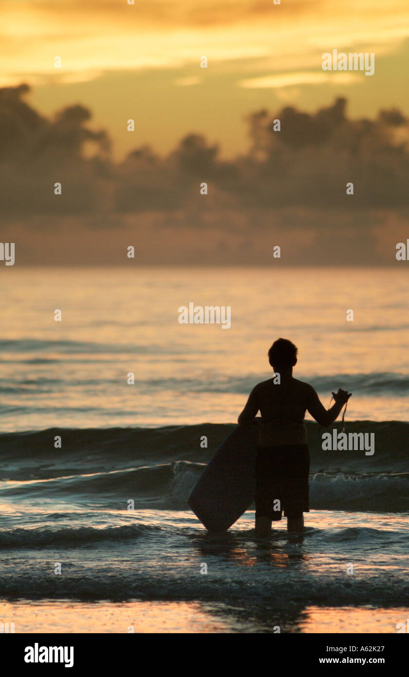 young boy walking into ocean with boogie board at sunrise children body ...