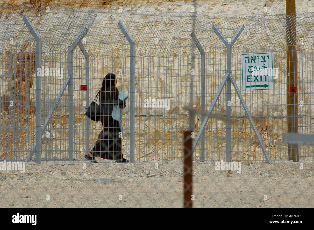 A Palestinian woman walks through perimeter fence at an Israeli ...