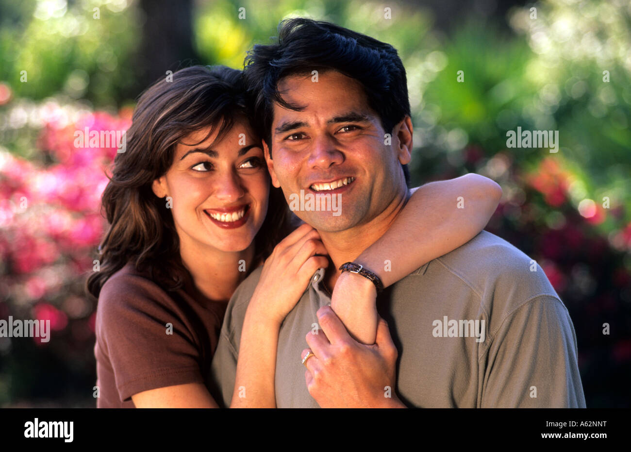 Attractive Hispanic couple outdoors with colorful background hugging ...
