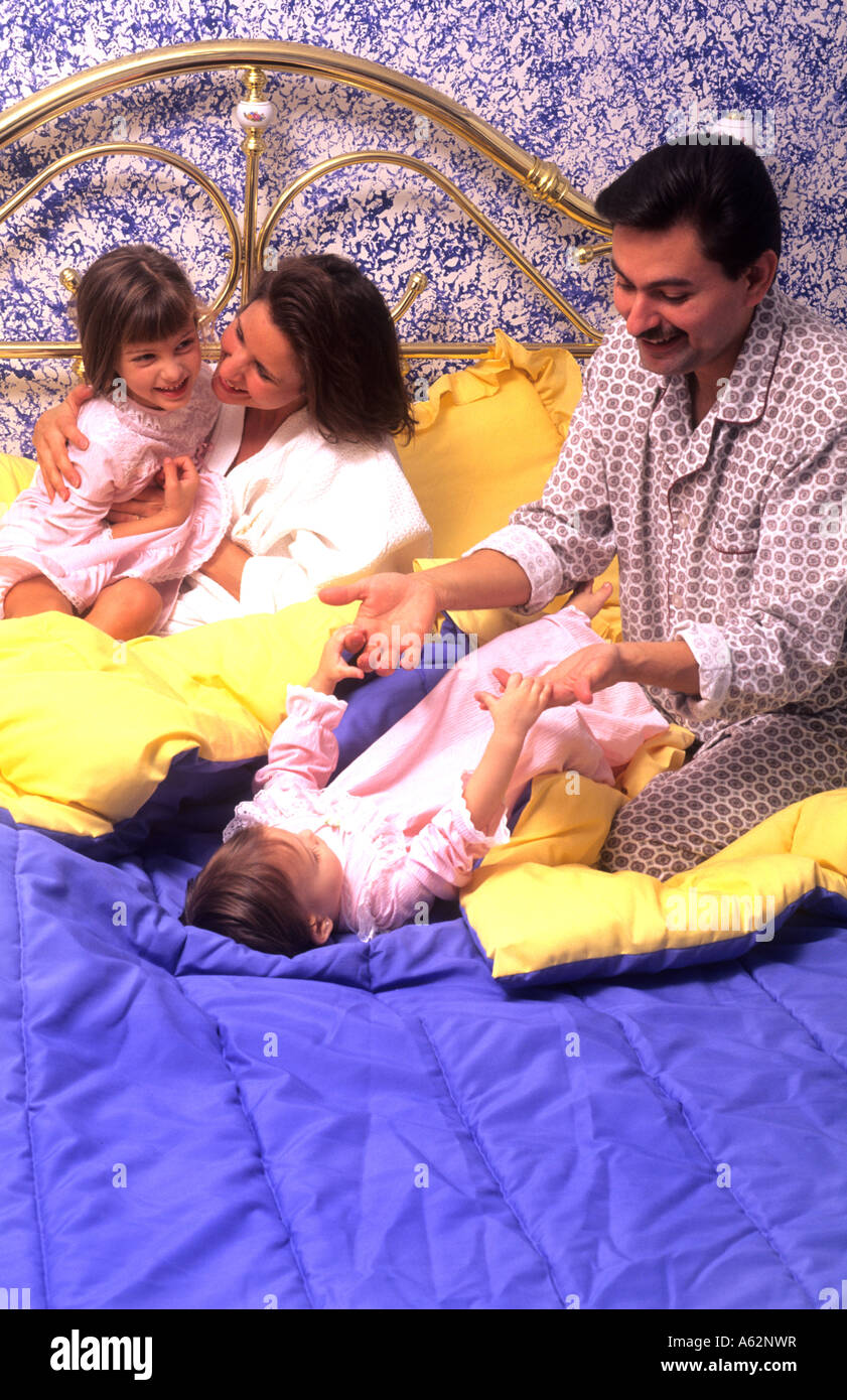 Hispanic family hugging and sharing love at home in pajamas in bed ...