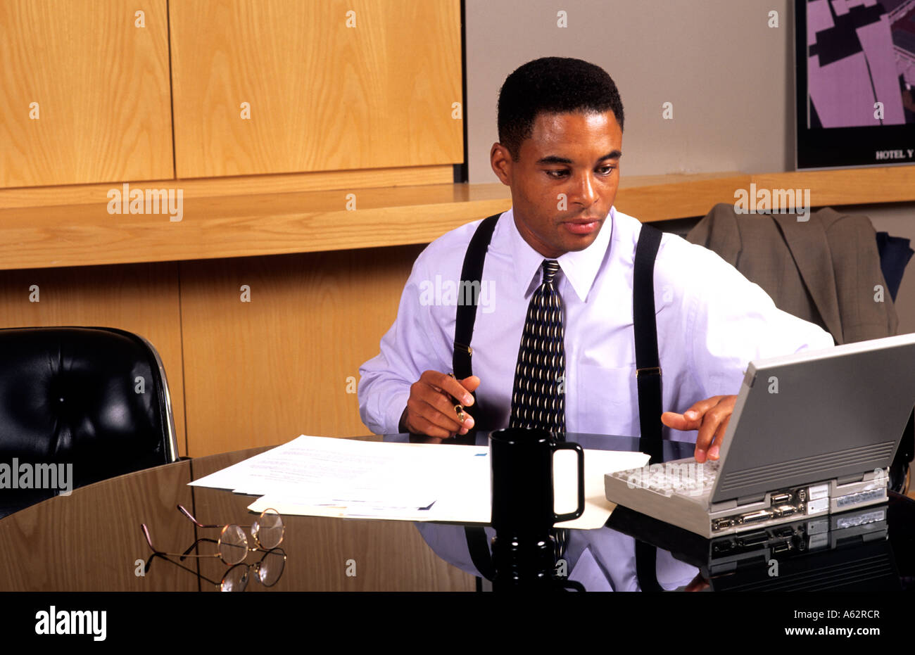 Attractive modern business man at desk in great setting in office ...