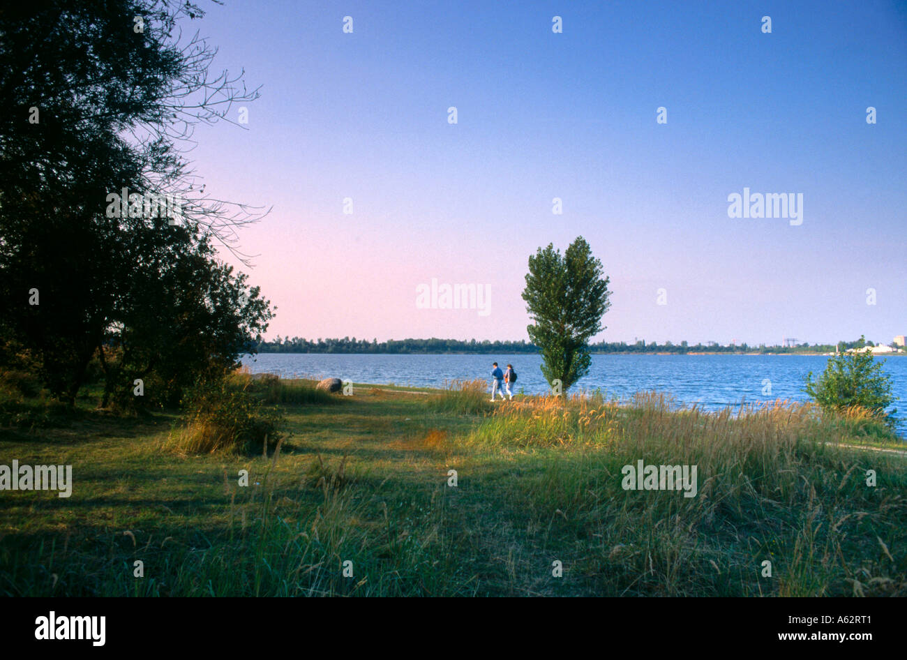 two people walking on the lakeside, Lake Kulkwitzer, Leipzig, Saxony ...
