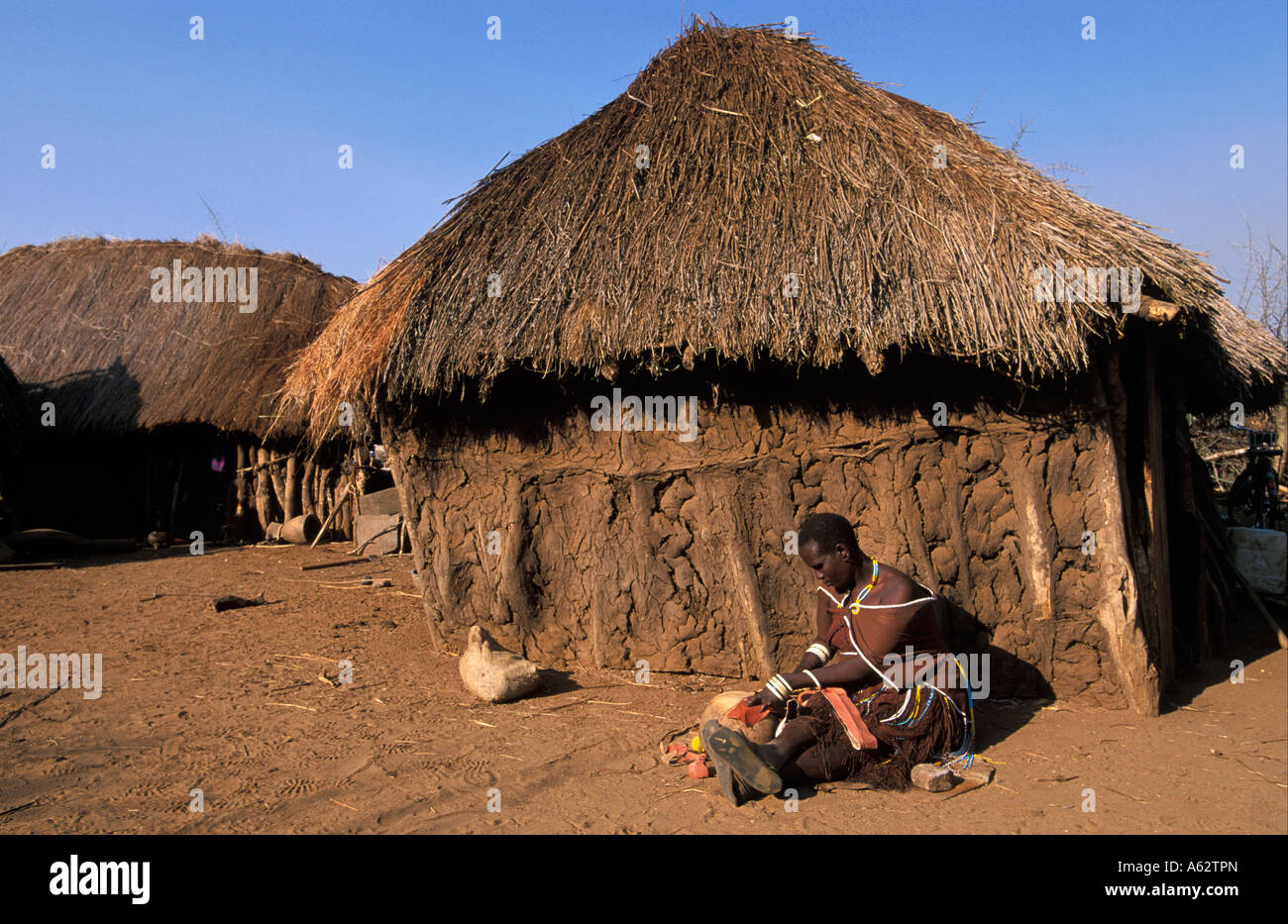 Barabaig women making a leather dress in front of her mud and thatch ...