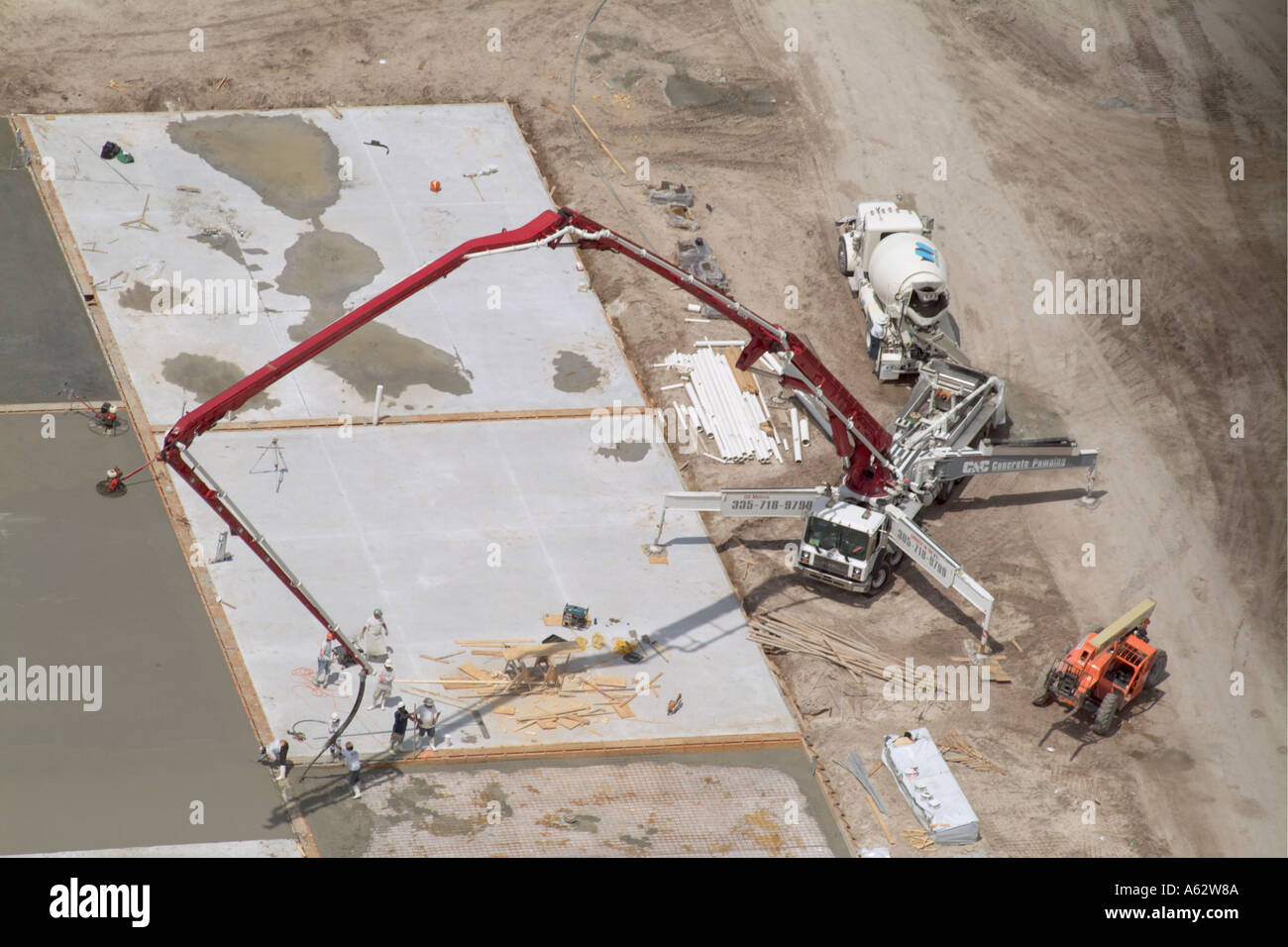 concrete pumping truck pouring slab at construction site workers ...