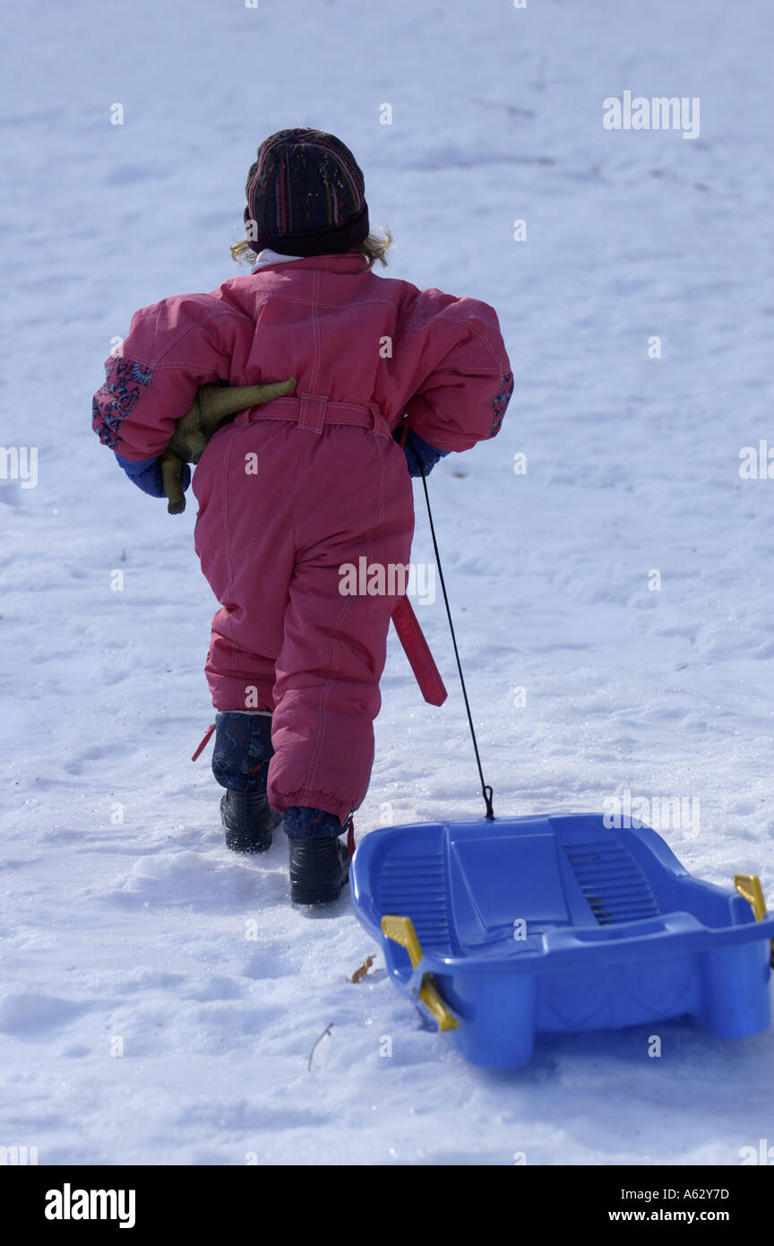 Young girl towing a sled along in the snow Stock Photo - Alamy