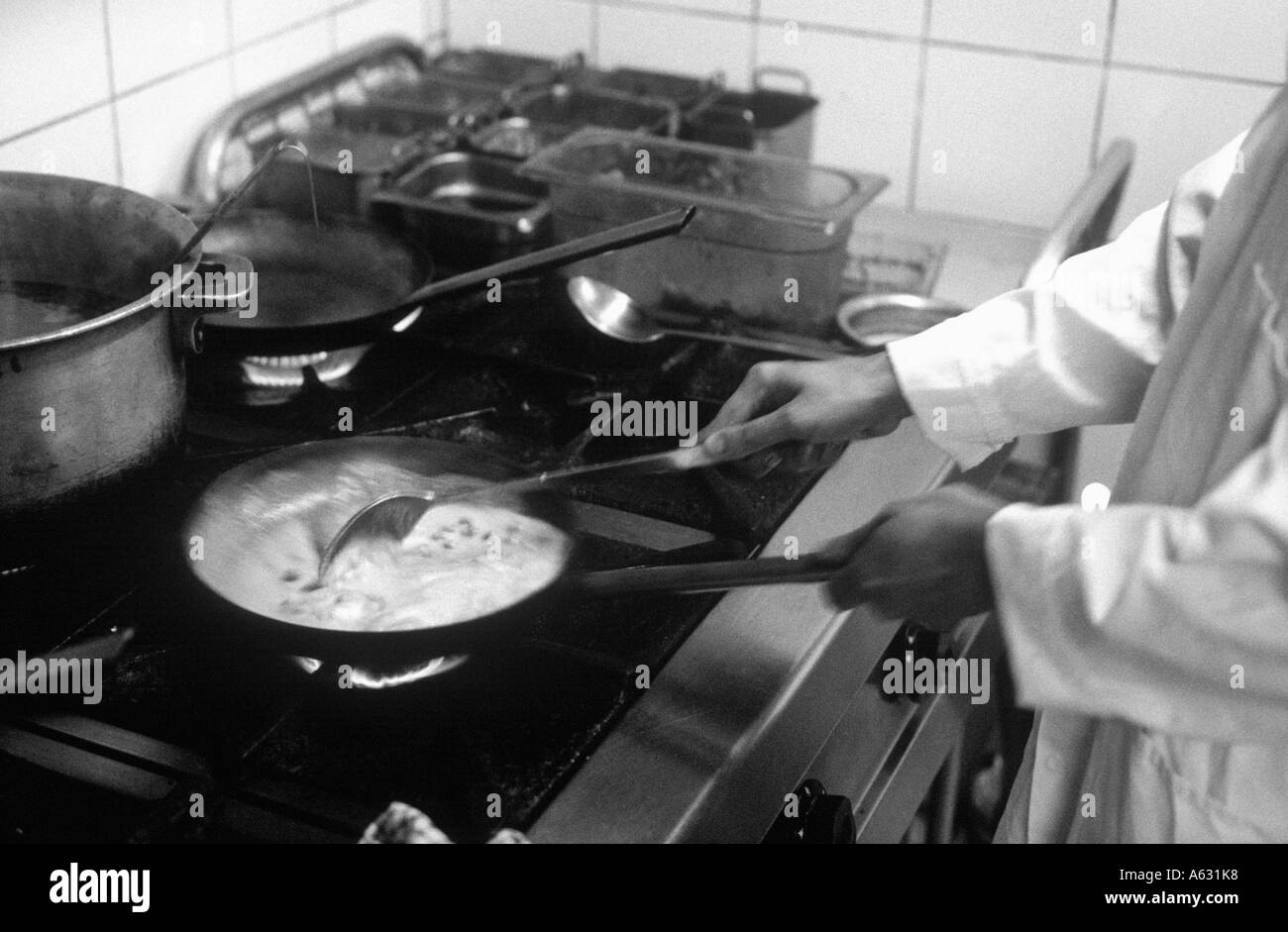 a chef cooking with a frying pan in a kitchen Stock Photo - Alamy