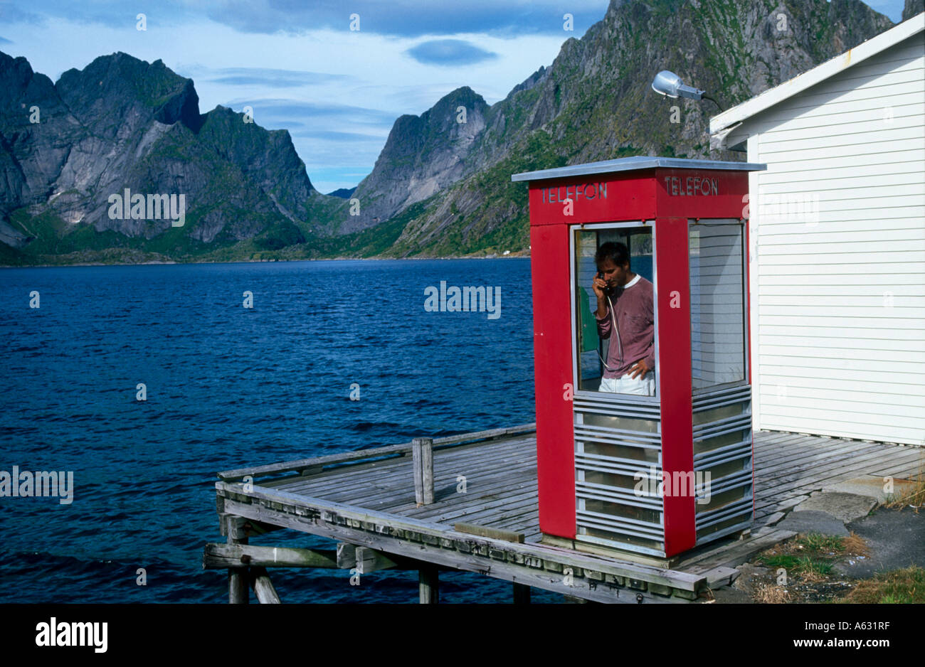 Person using the landline phone inside a telephone booth Fjords Norway ...