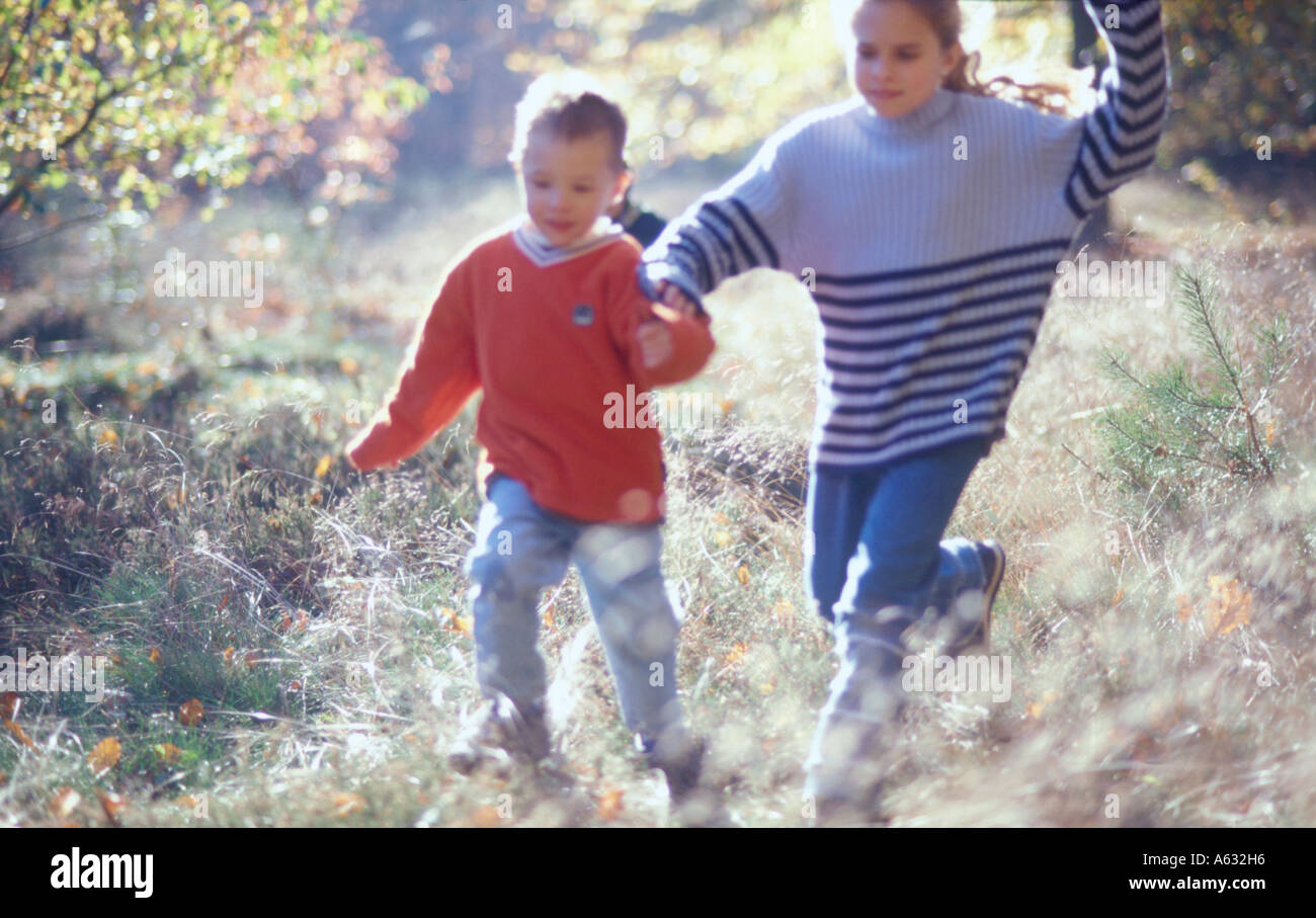 Brother and sister running in forest Stock Photo - Alamy
