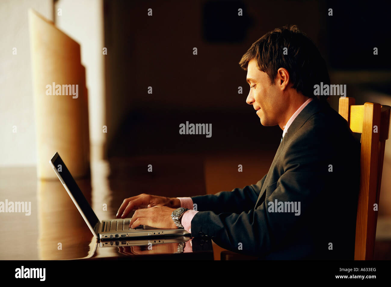 Side profile of a businessman typing on a laptop Stock Photo - Alamy