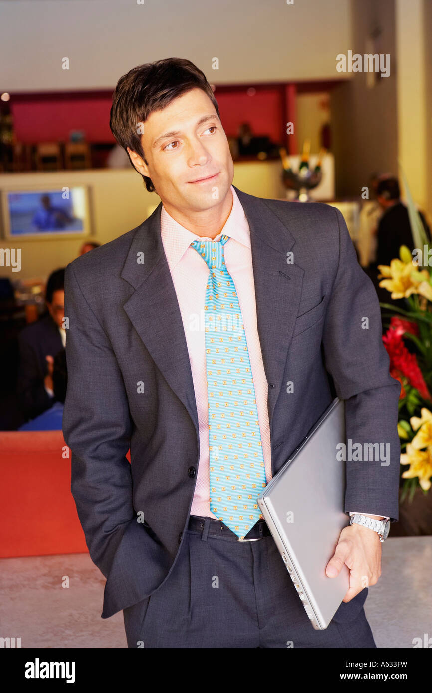 Businessman standing and holding a laptop Stock Photo - Alamy