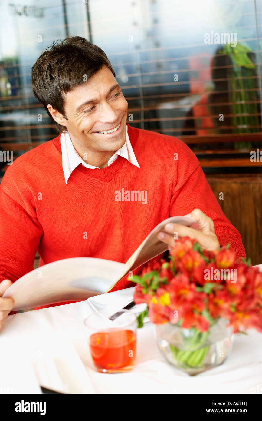 Mid adult man holding a menu in a restaurant and smiling Stock Photo ...