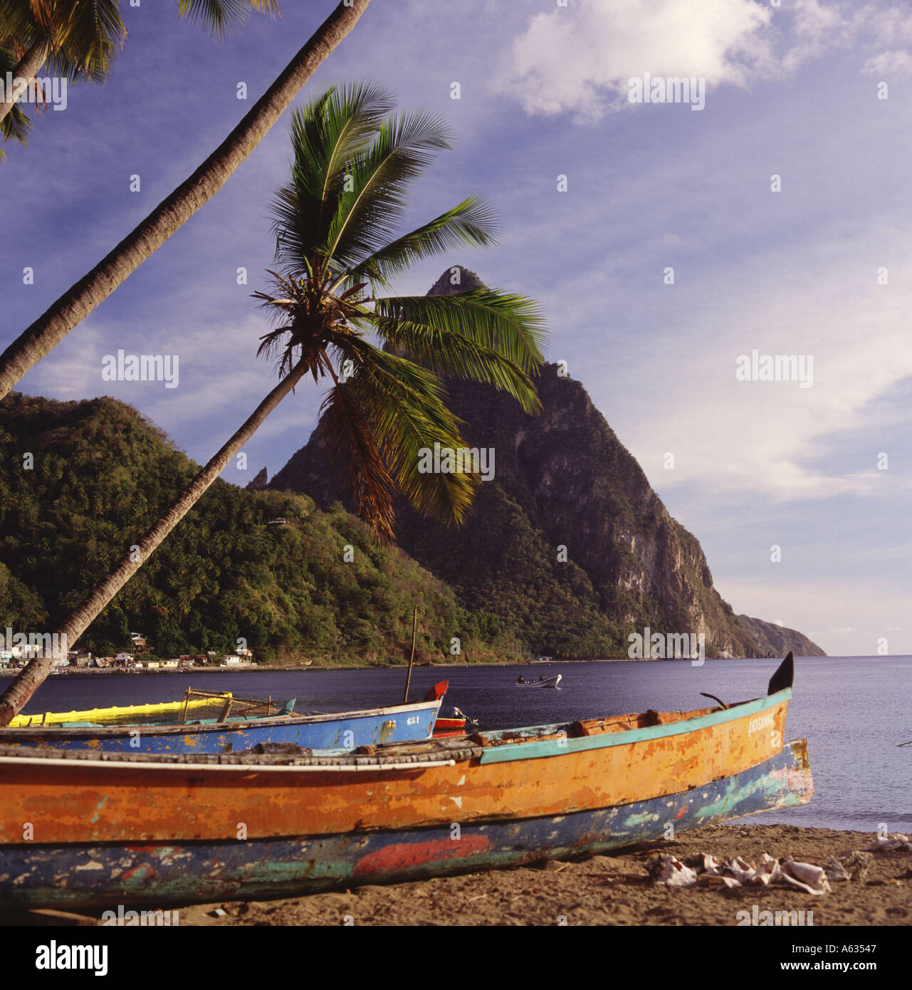 Local boats on beach under leaning coconut palm tree at Soufriere with ...