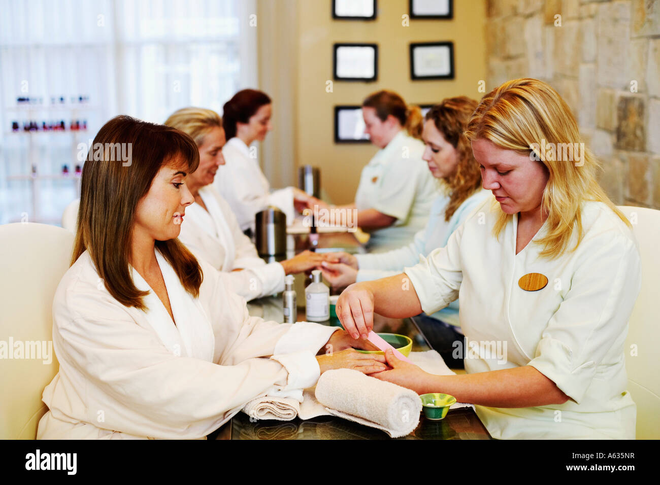 Three mature women getting manicure by beauticians Stock Photo - Alamy