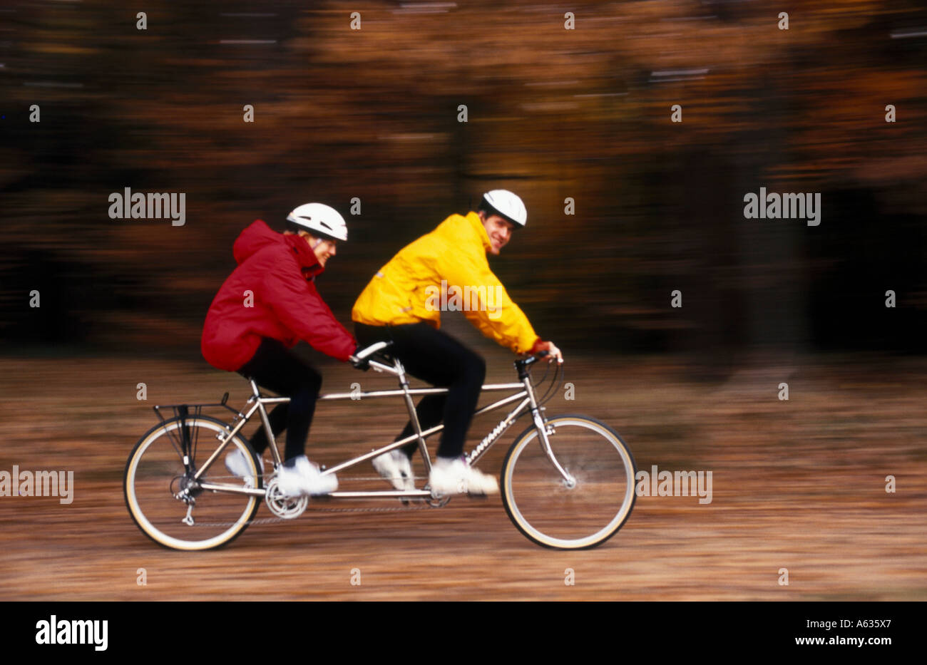 Side profile of couple riding tandem bicycle Stock Photo - Alamy