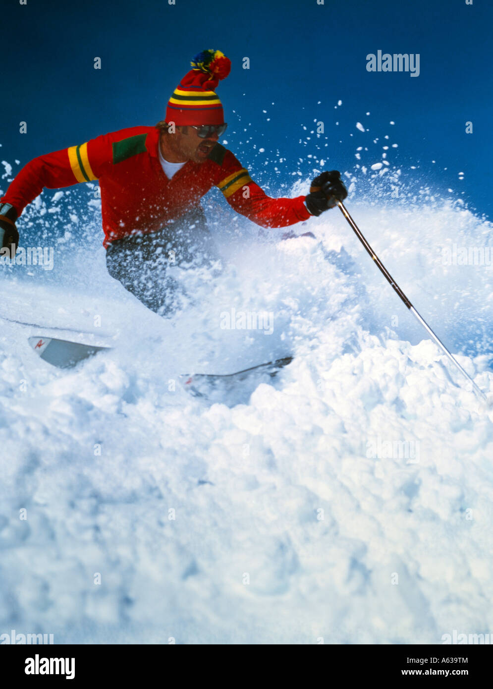 Expert skier throws up clouds of snow as he carves a turn on a steep ...