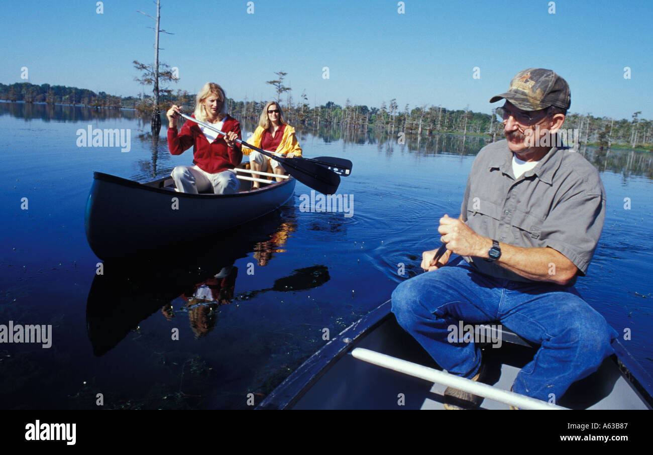 Guide and two beautiful young women in canoes on Black Bayou Lake near ...