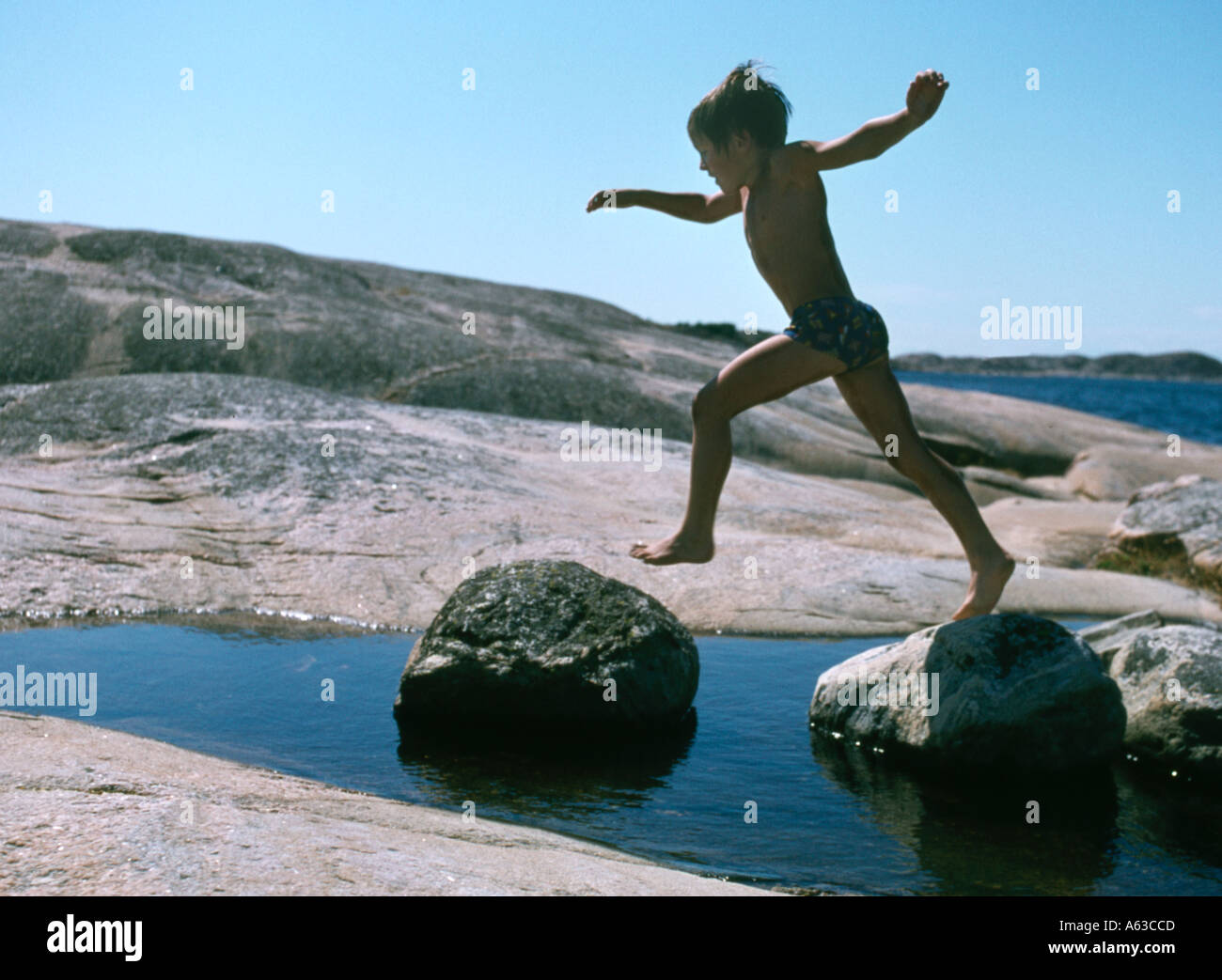 Child jumping over rocks Stock Photo - Alamy