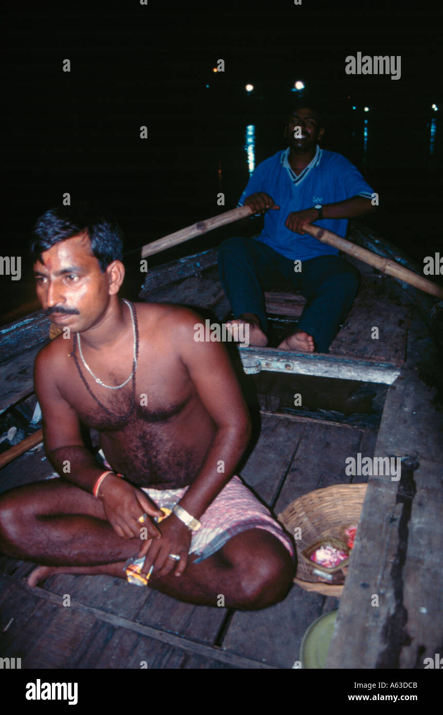 Indian man and boatman rowing boat on the river Ganges at night ...