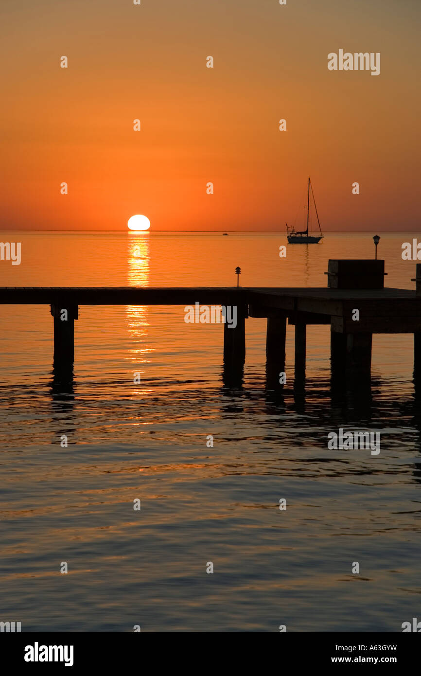 The sun disappearing below the horizon A boat moored in the calm water ...