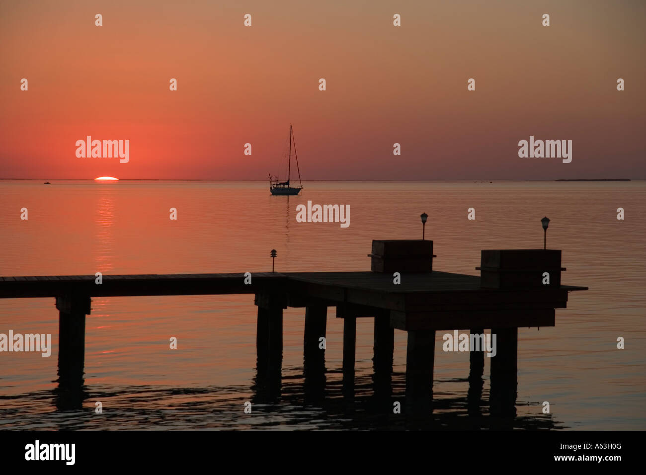 The sun disappearing below the horizon A boat moored in the calm water ...