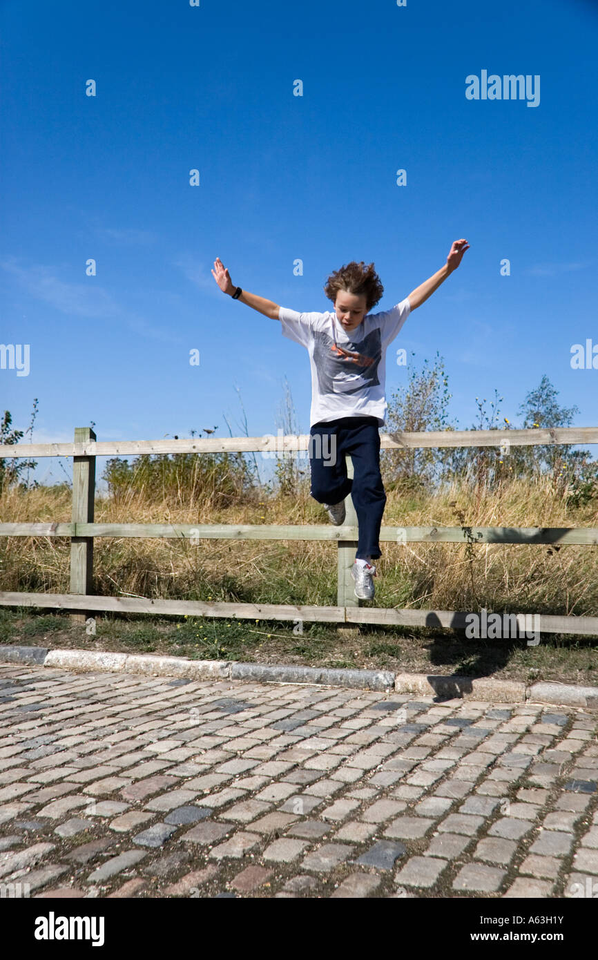 a ten year old boy jumping off a fence onto a cobblestone road Stock ...
