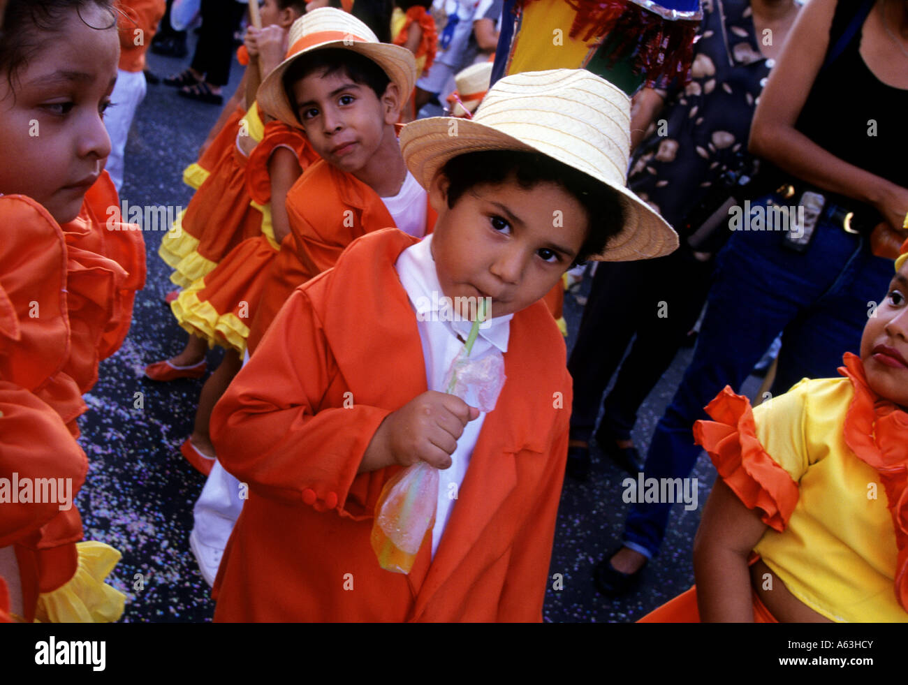 Boy in orange jacket, drinking orange juice, at childrens’ carnival ...