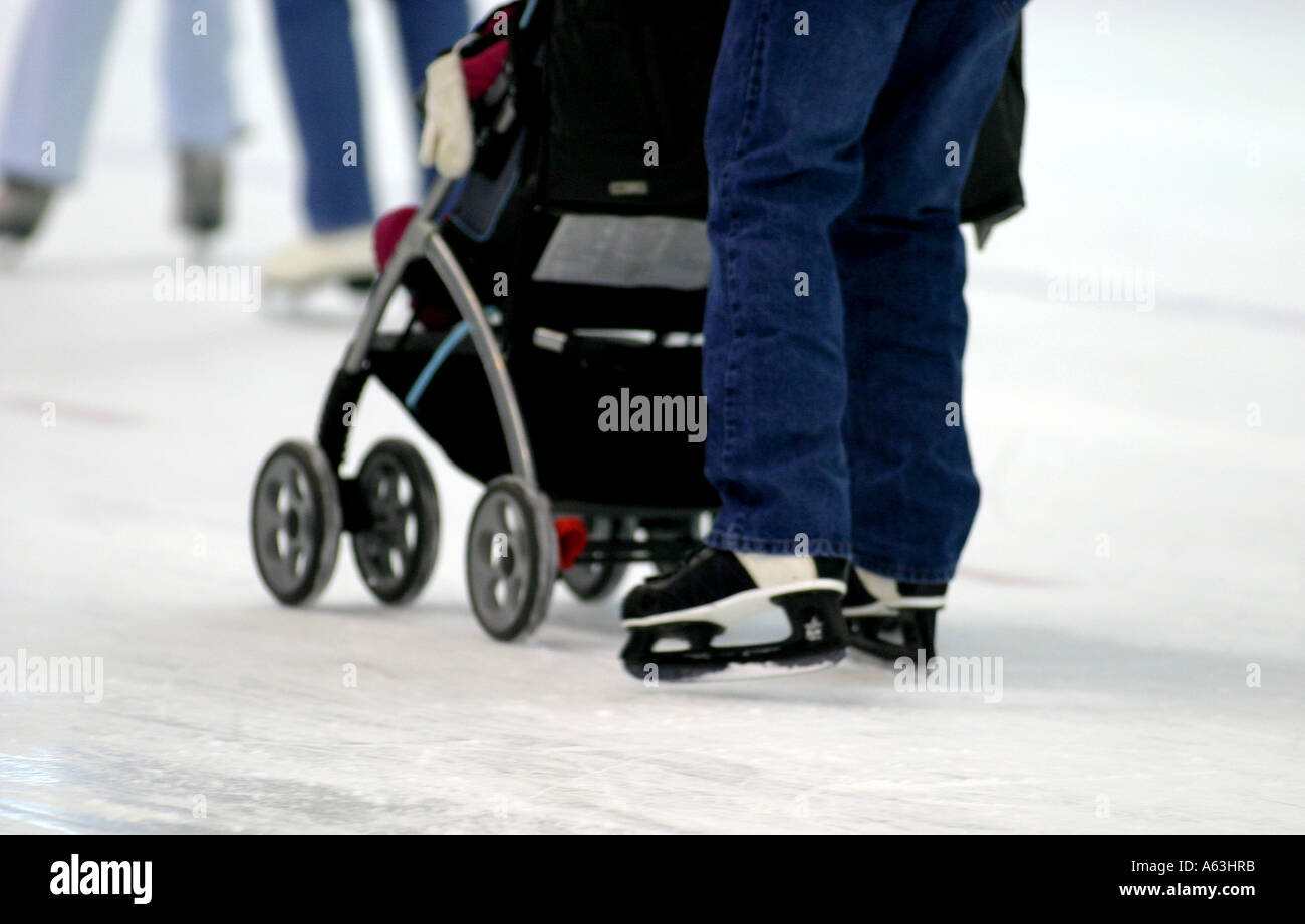 Parent taking a young child on the ice rink in a stroller Stock Photo ...