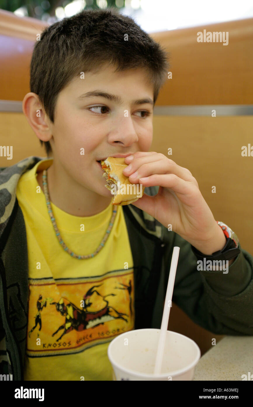 young boy eating a hamburger at a fast food restaurant Stock Photo - Alamy
