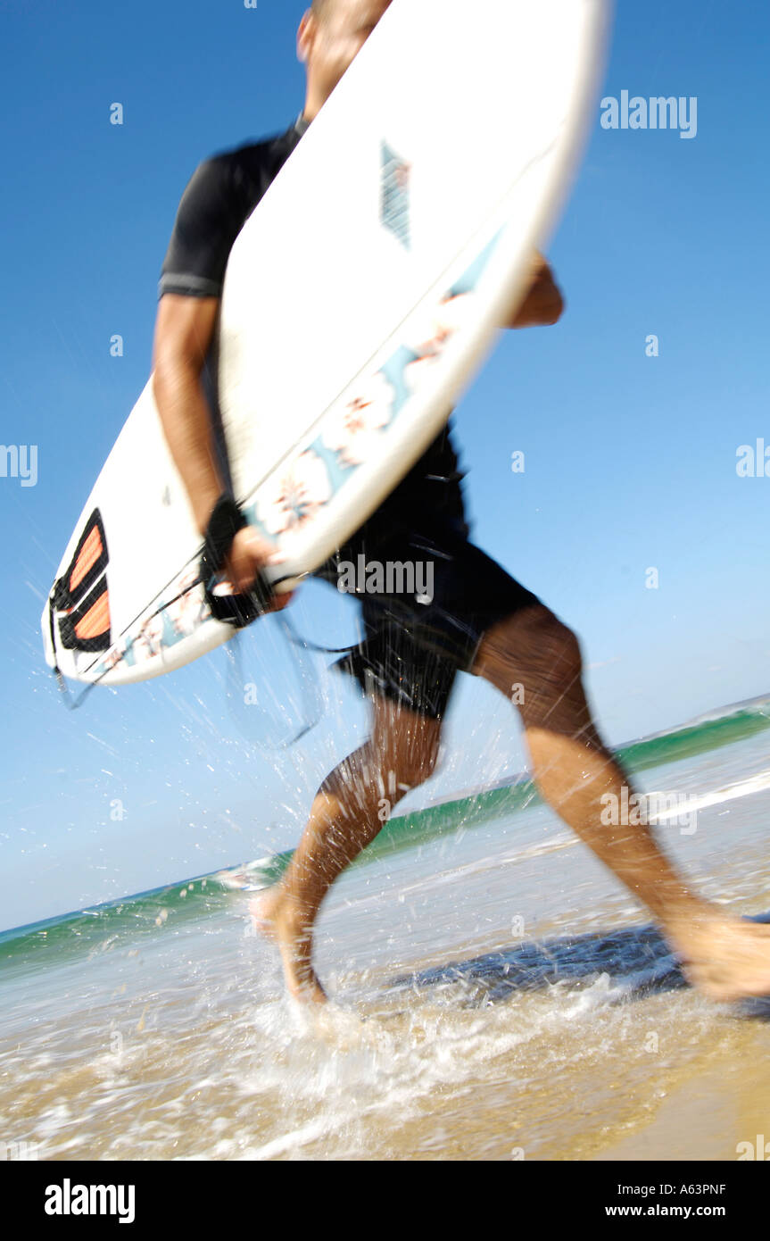 Man running with surfboard on beach Stock Photo - Alamy