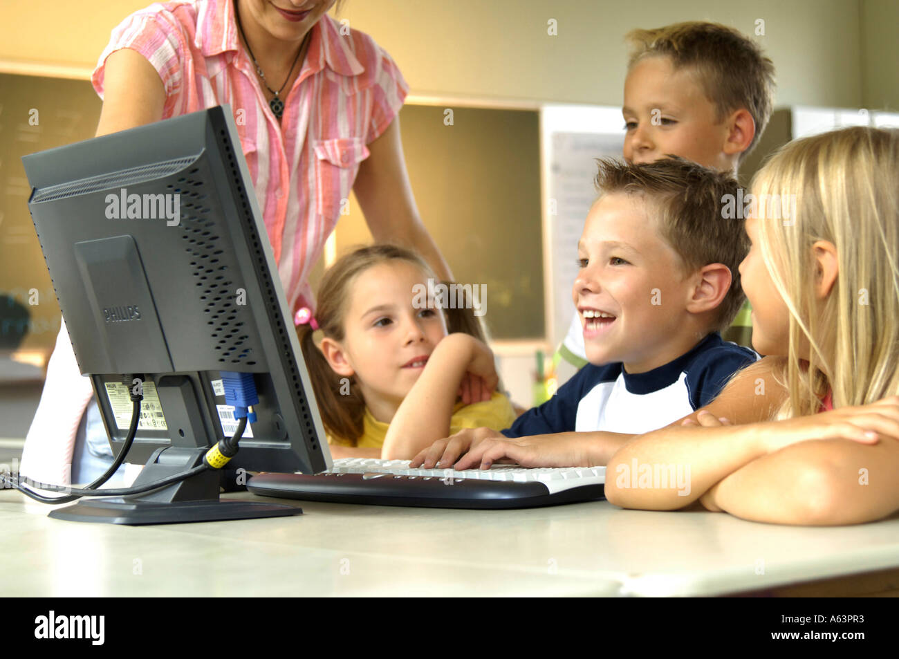 Four students and teacher looking at computer monitor Stock Photo - Alamy