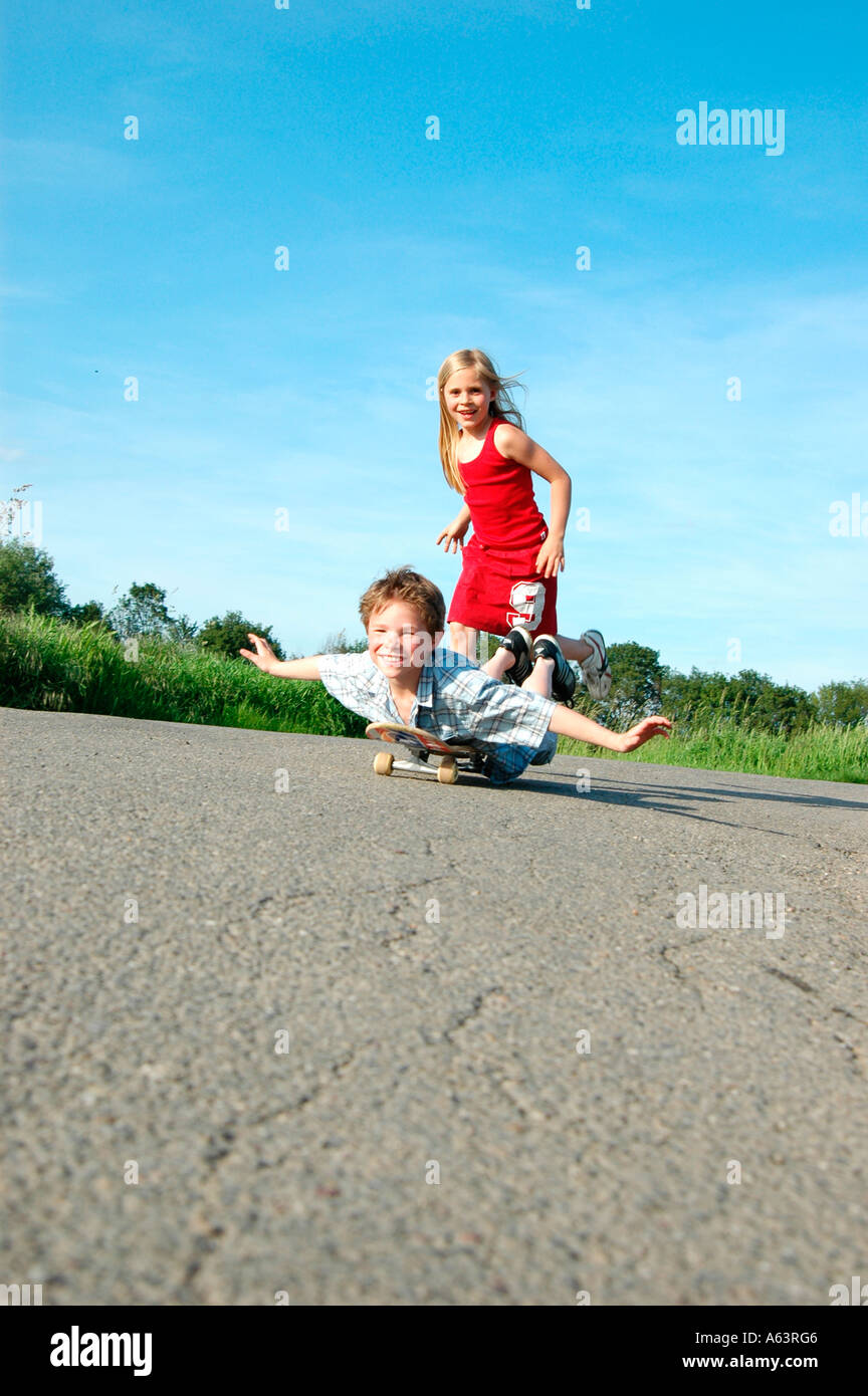 Girl pushing her brother on a skateboard Stock Photo - Alamy